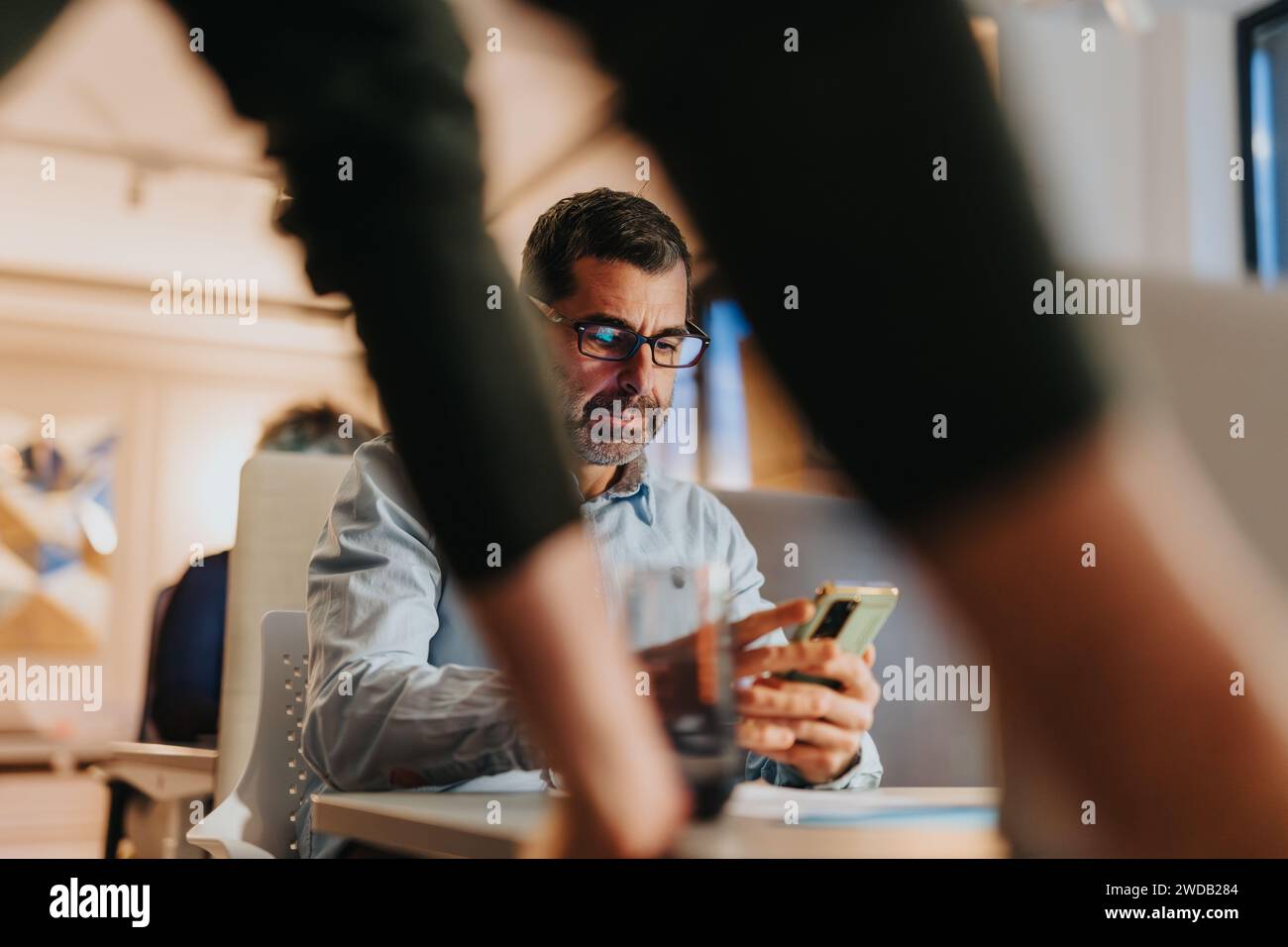 Taking a break from work, the businessman checks his phone, catching up ...