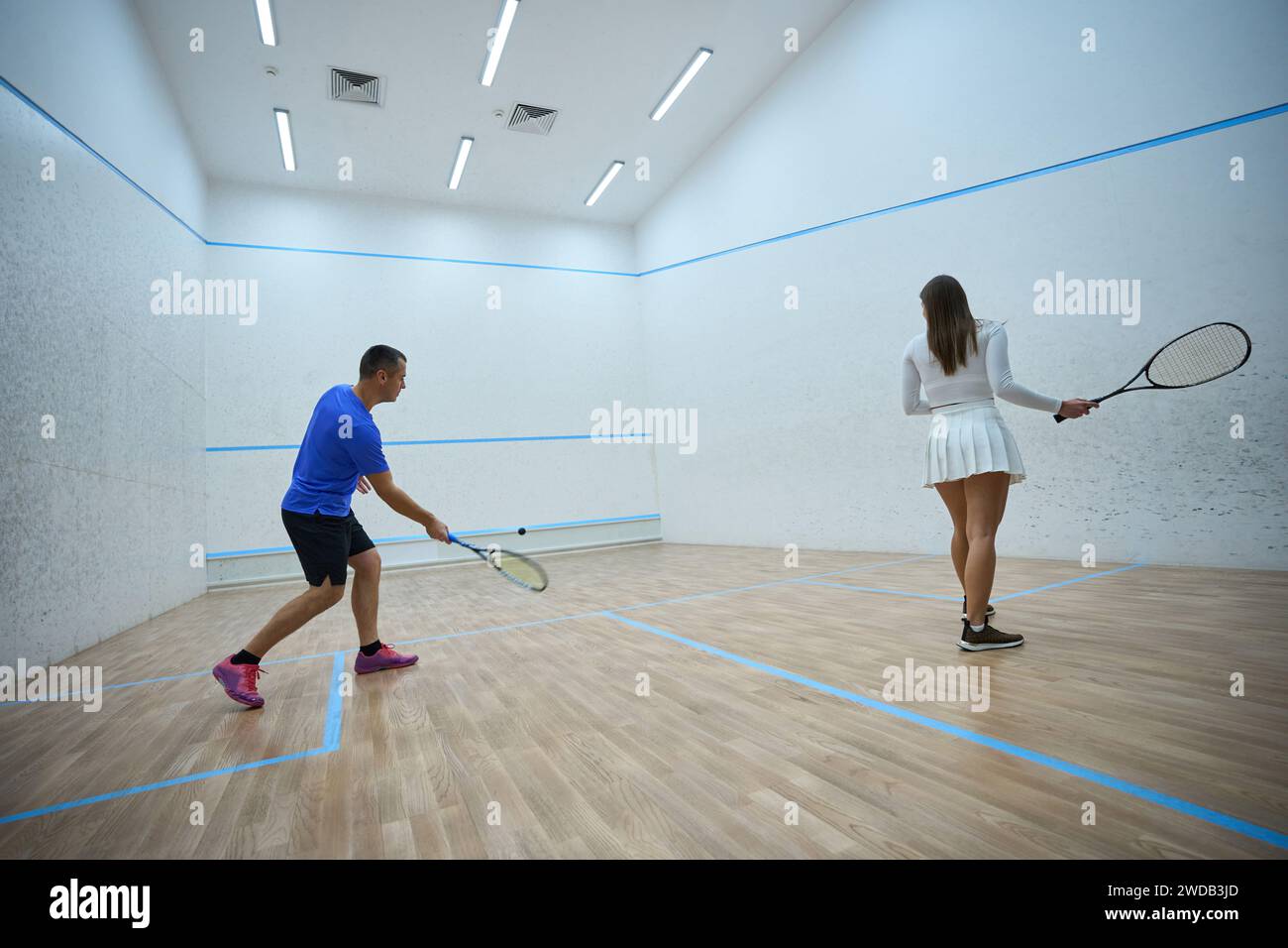 Energetic sportswoman practices refining hitting skills with squash man ...
