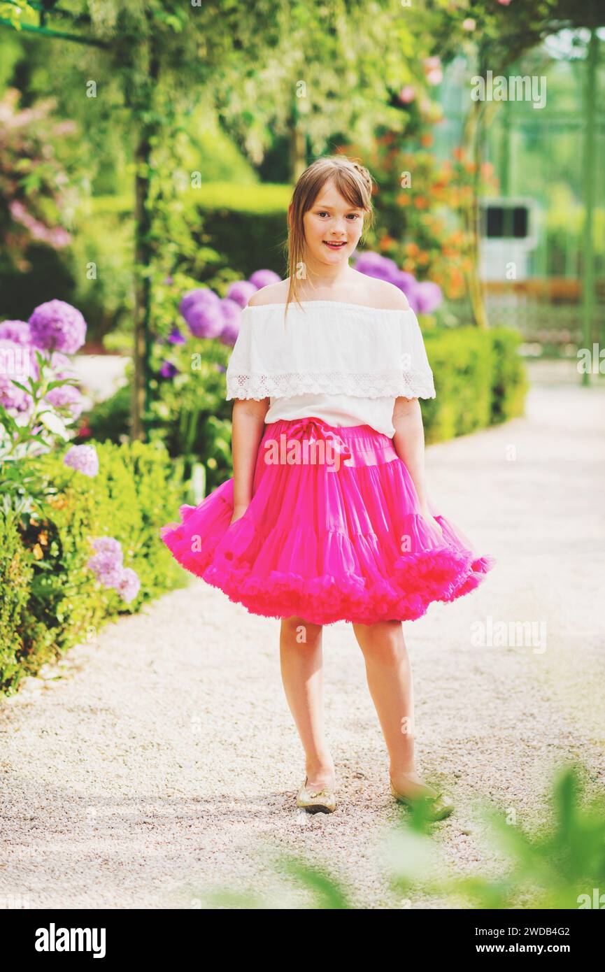 Pretty little 9-10 year old girl playing in beautiful garden, wearing ...
