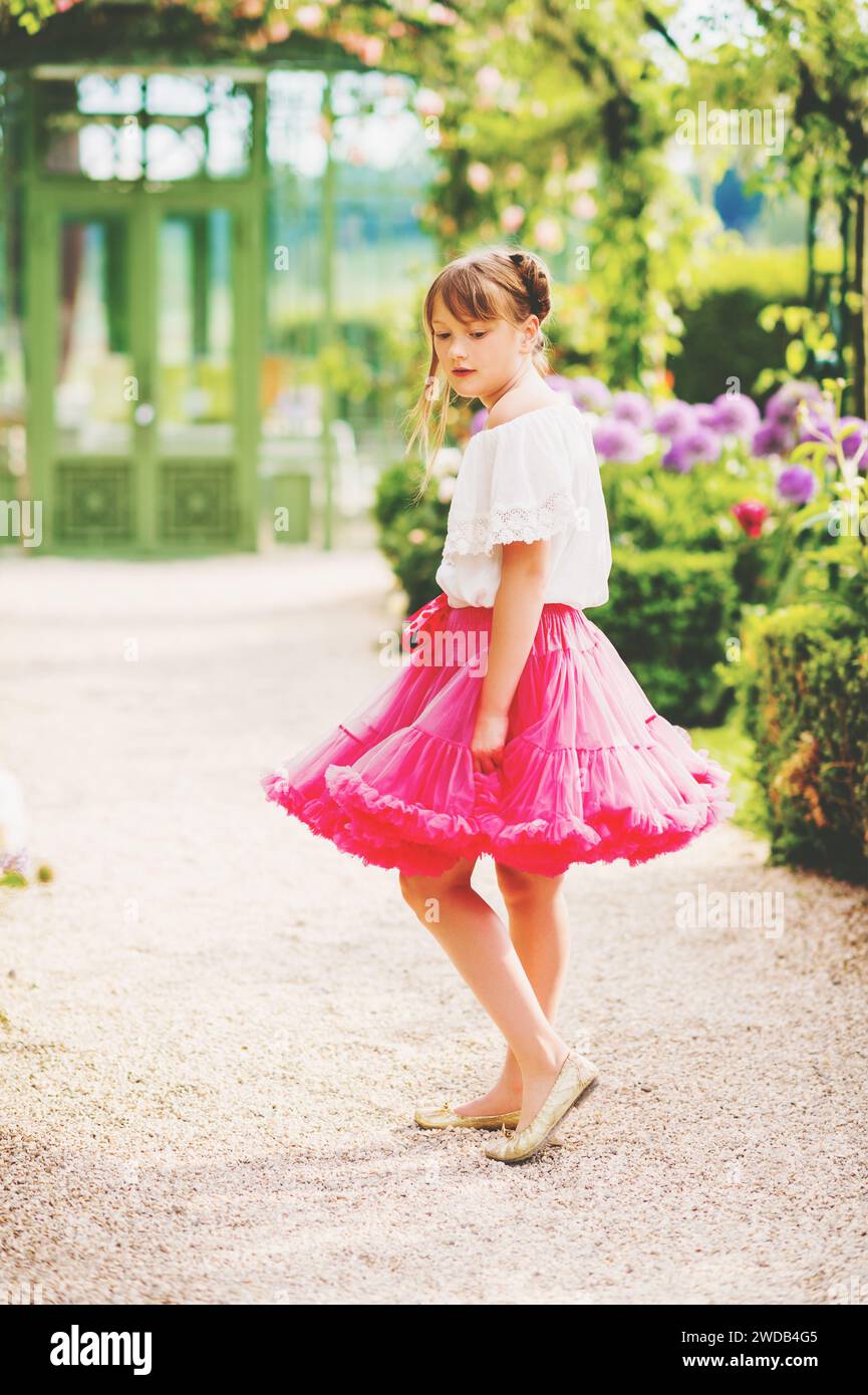 Pretty little 9-10 year old girl playing in beautiful garden, wearing ...
