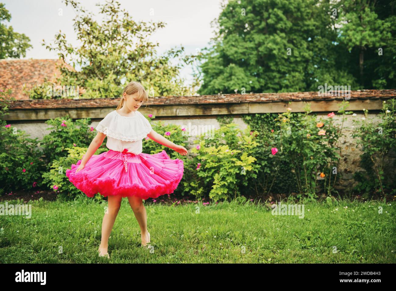 Sweet little kid girl dancing in a beautiful flower garden on a nice ...