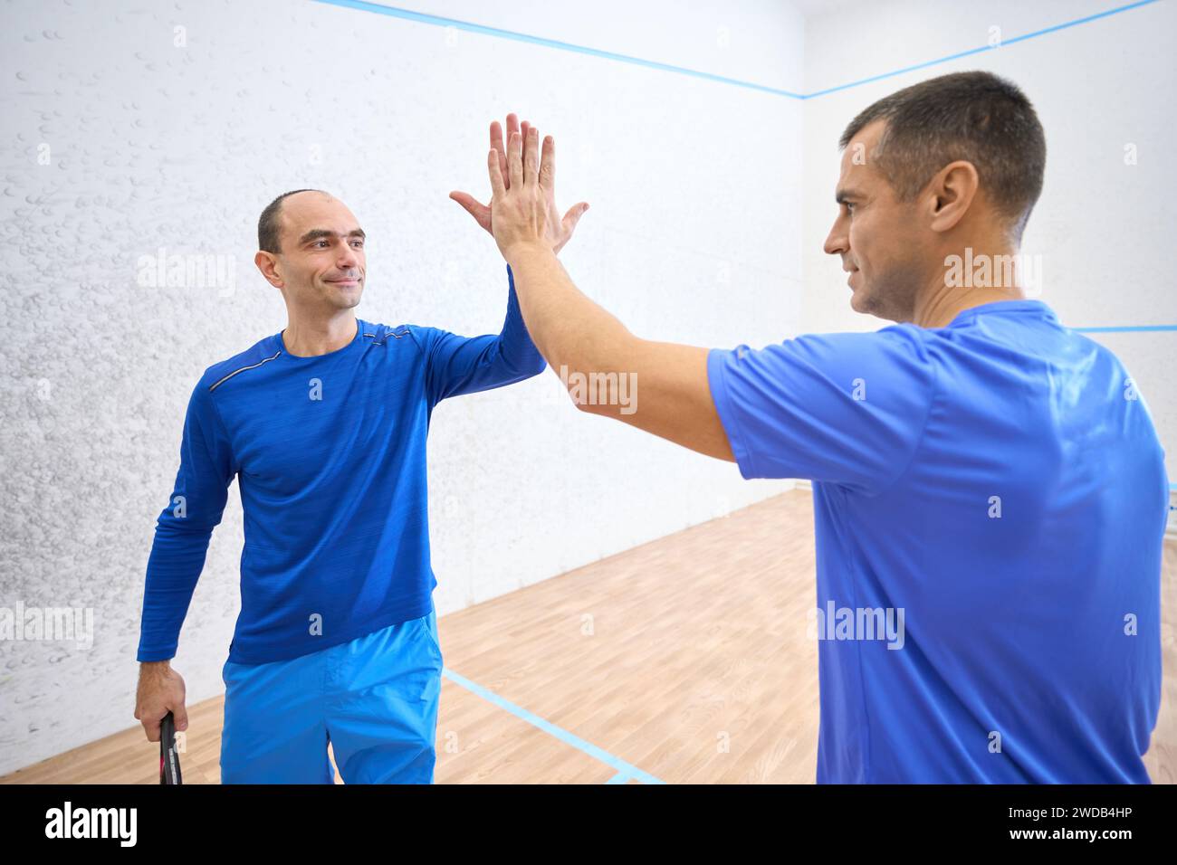 Two active squash players giving high five after game Stock Photo - Alamy