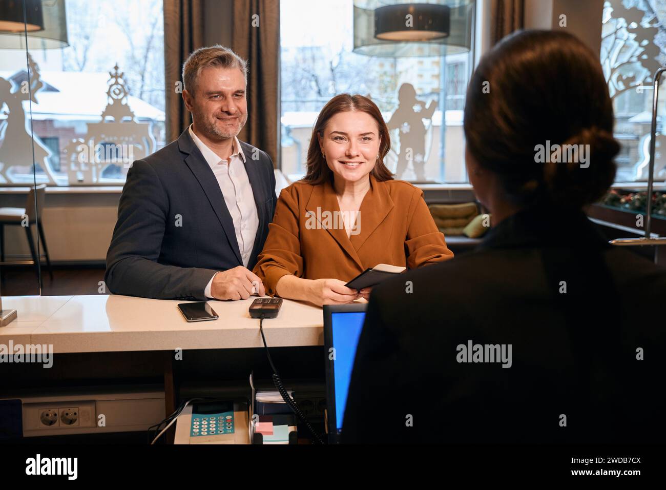 Caucasian couple looking at female reception desk during check-in in ...