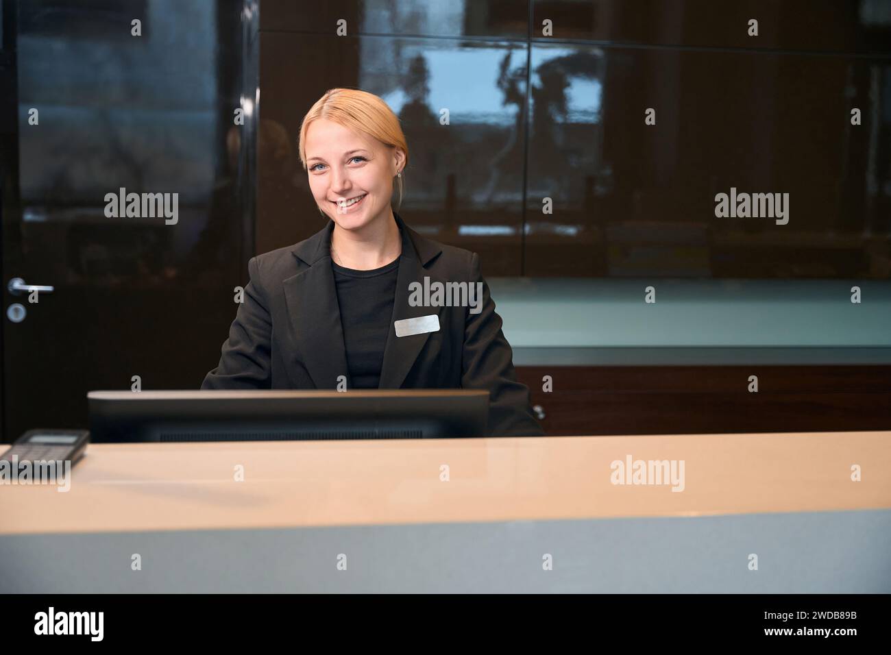 Young smiling european female receptionist at reception desk in hotel ...