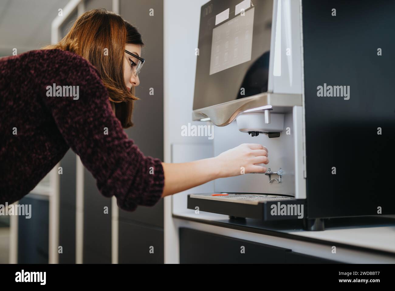 A photo of gorgeous female person taking a coffee from the coffee maker ...