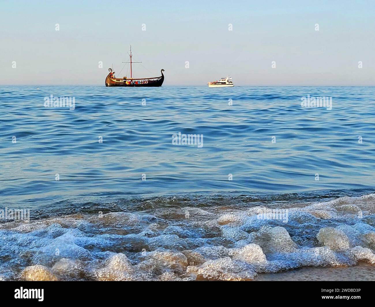 Two sea vessels met in the blue sea - a ship from the Viking era and a ...