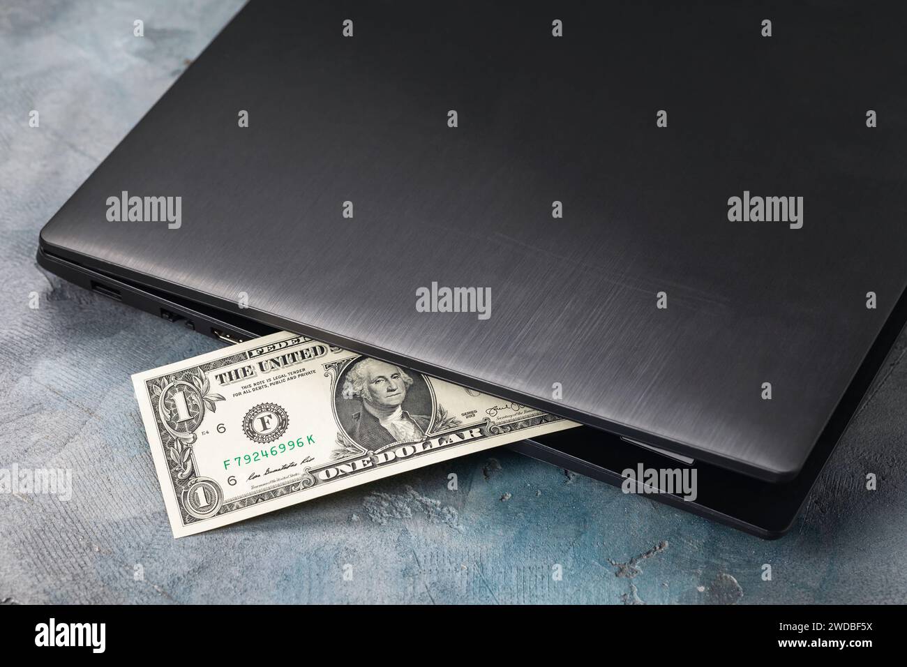 Dollar sticking out of a laptop, concept on the topic of remote work ...