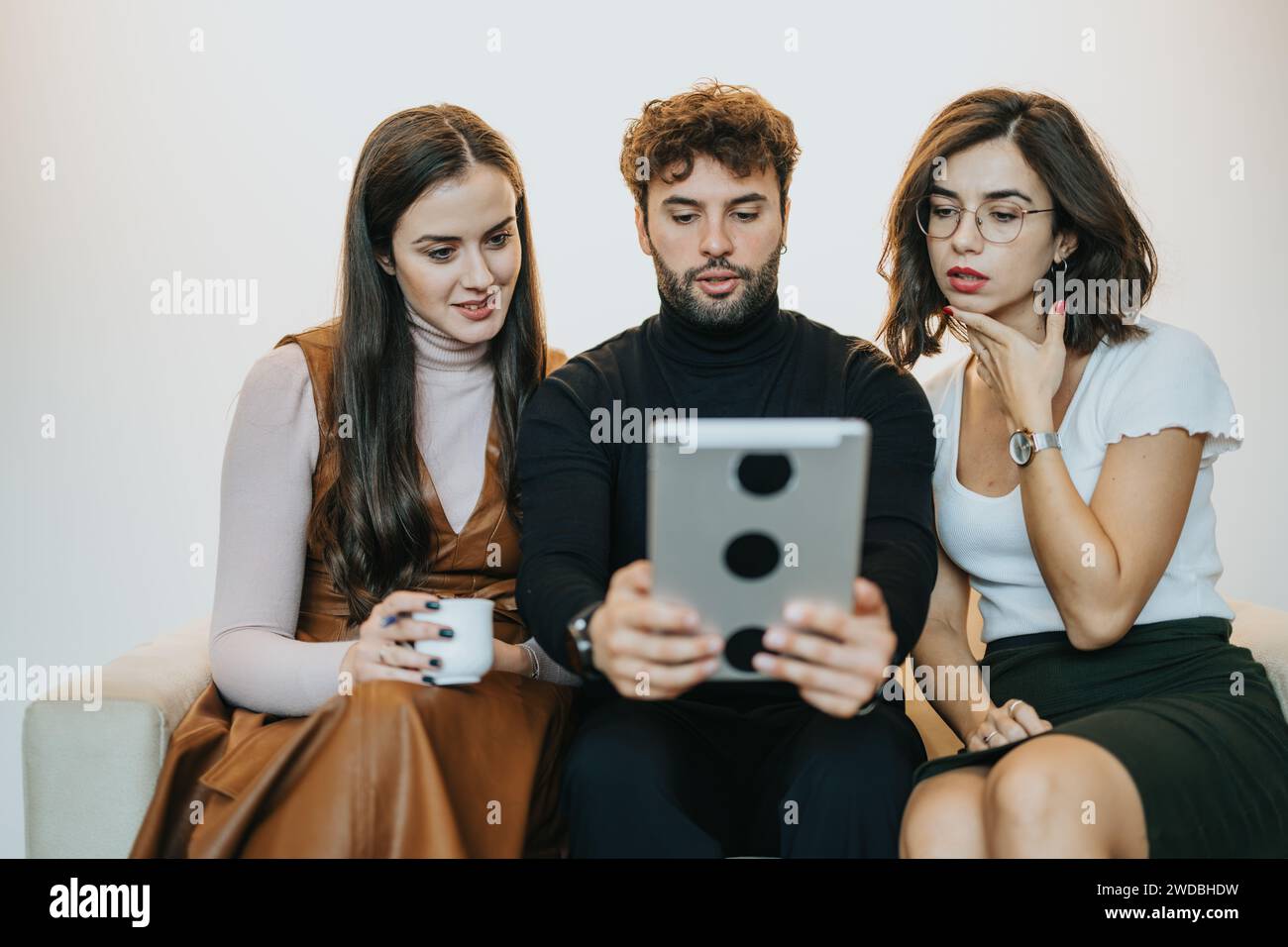 Three young professionals engaging in a collaborative discussion over a digital tablet in a ...