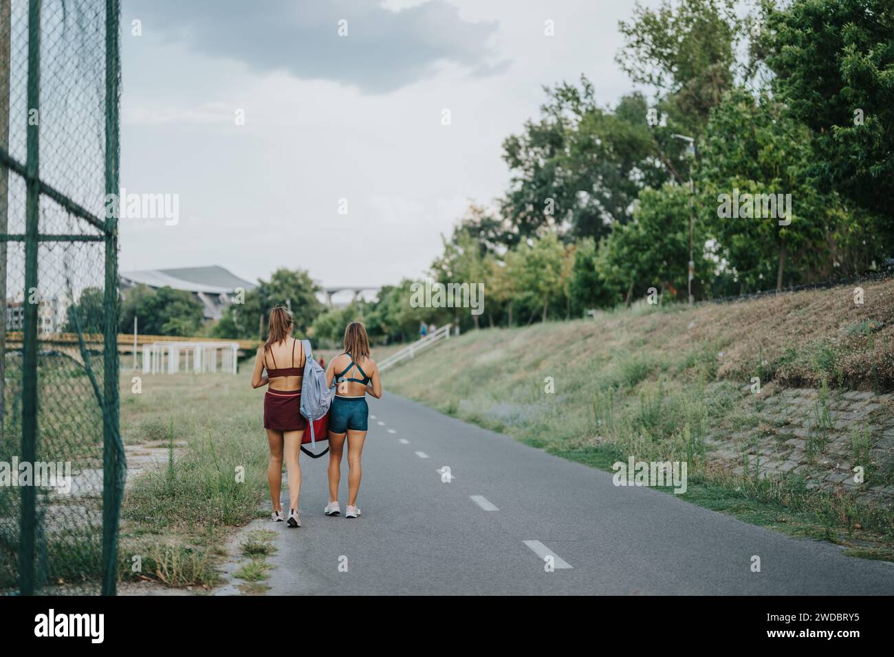 Fit girls walking on a track after training at the park. They are going ...