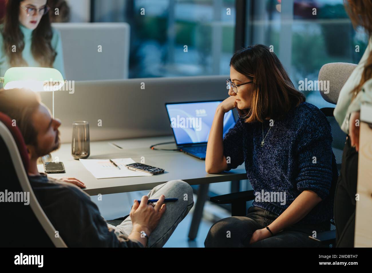 A dedicated team collaborates on a project late into the evening in a ...