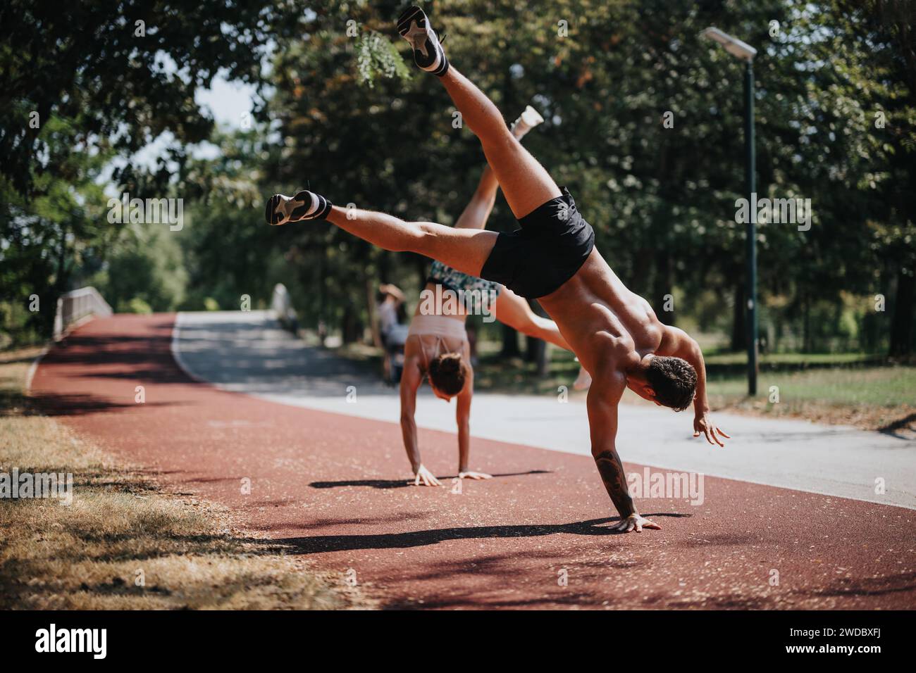 Outdoor Duo Athletes Practice Cartwheel in Sunny Park Stock Photo - Alamy