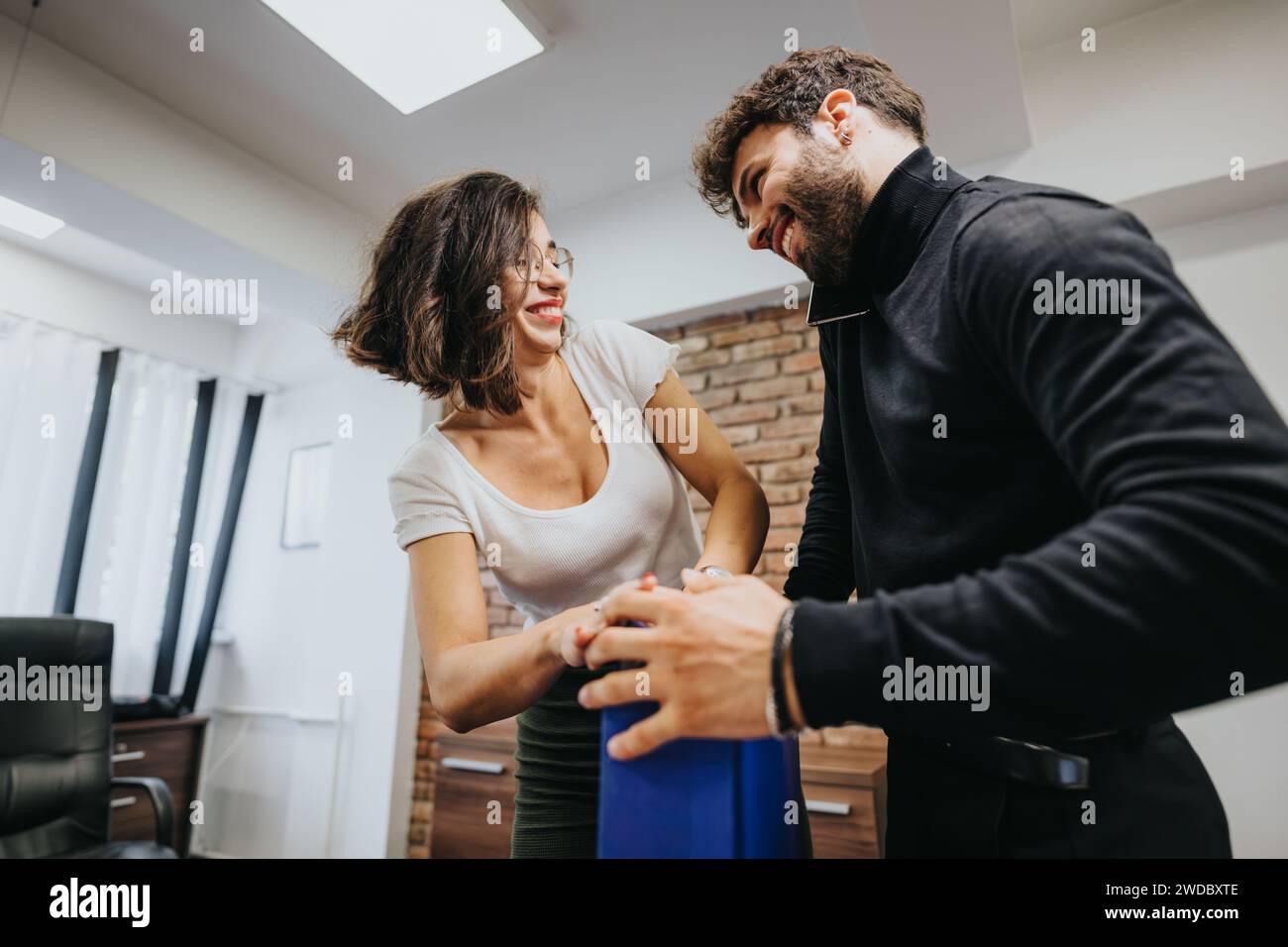 Energetic young professionals in casual office attire enjoying teamwork ...