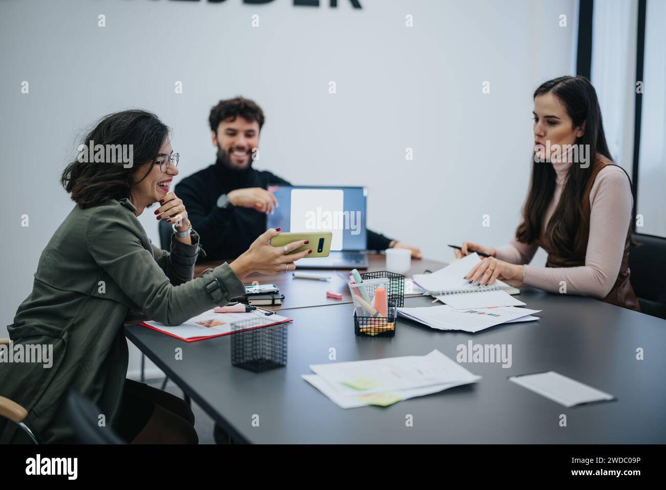A group of young people engages in a lively discussion around a table ...