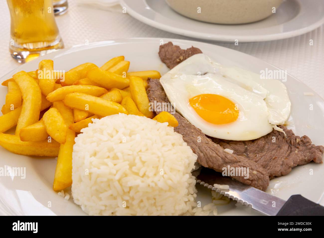Rice with fried egg and beef on a plate in a restaurant. "Prego no ...