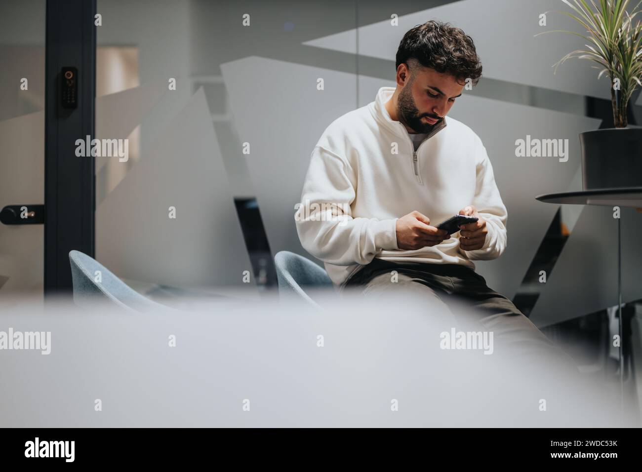 Taking a break, a man glances at his phone, staying connected at work ...
