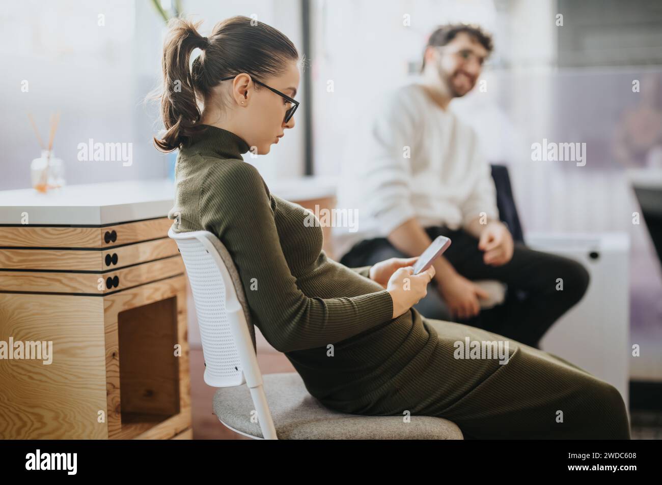 Woman checking phone during meeting Stock Photo - Alamy