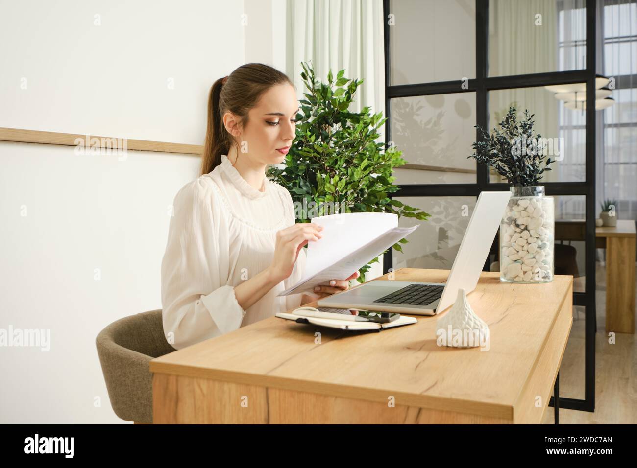 Young woman fills paper documents into digital database in the office ...