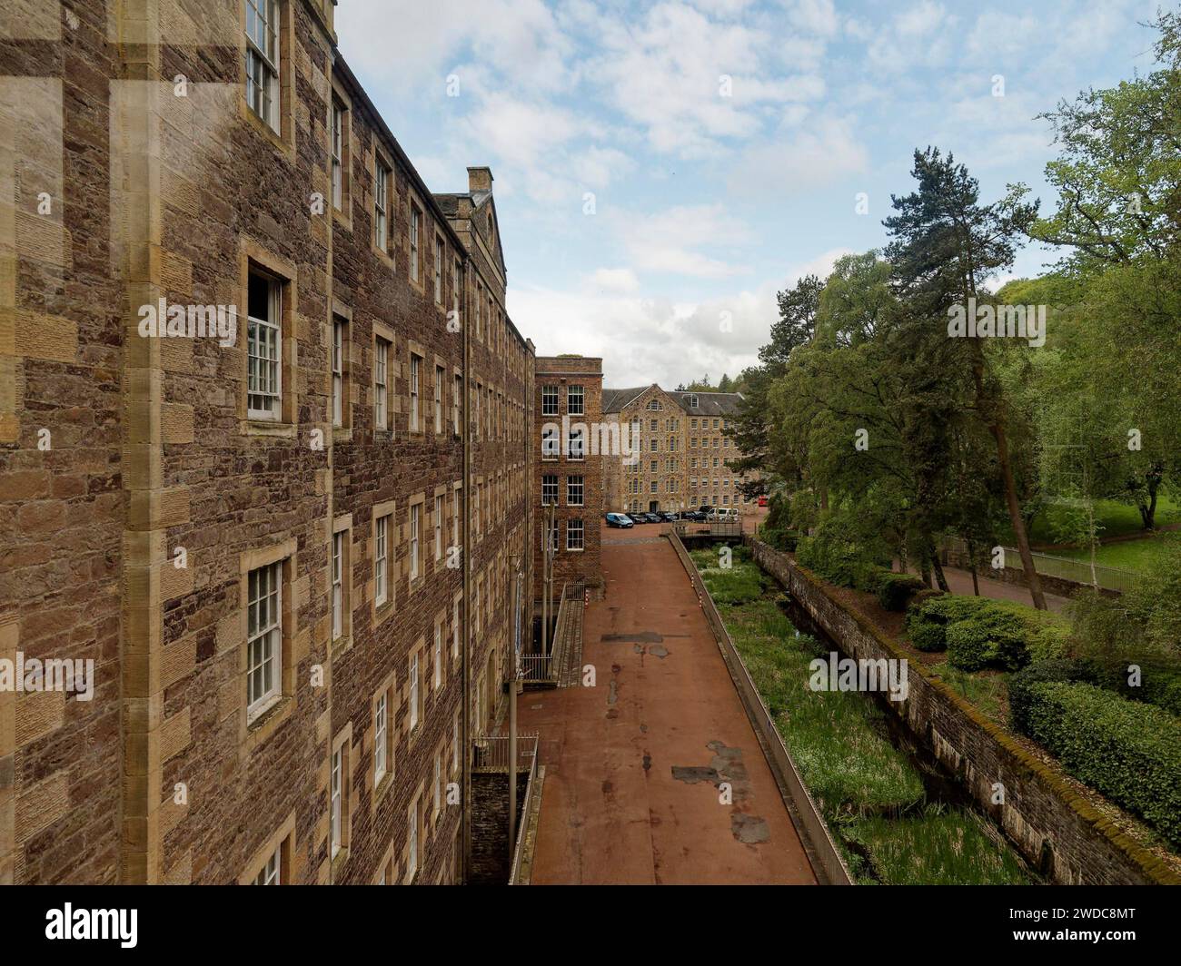 View of old buildings next to a street, surrounded by trees under a ...