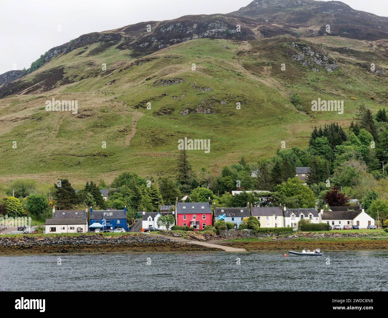Small settlement with colourful houses on a riverbank in front of green ...