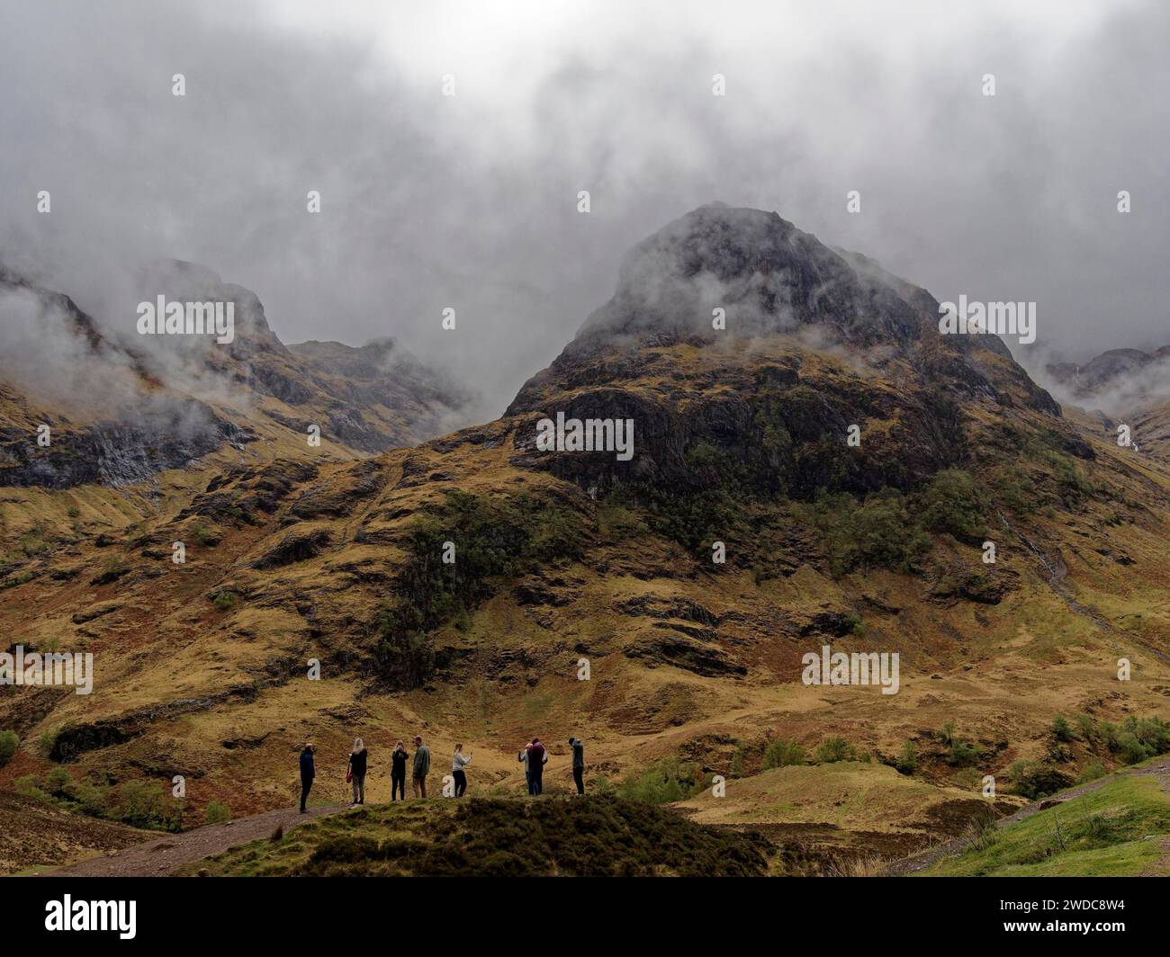 Visitors in front of misty mountain peaks in a dramatically beautiful ...