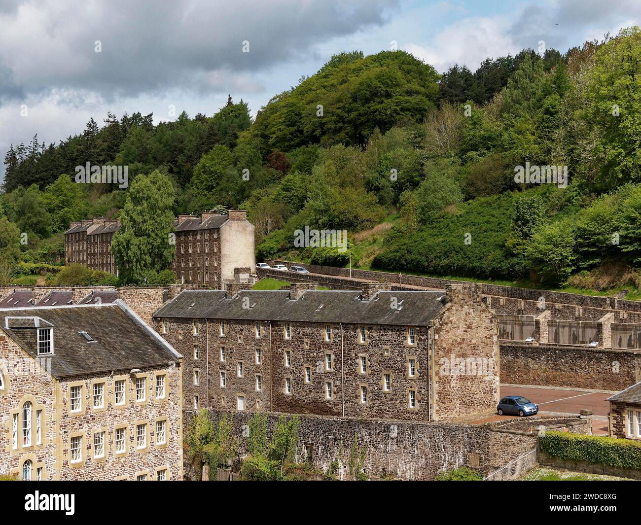 View of historic stone buildings in front of wooded hills on a cloudy ...
