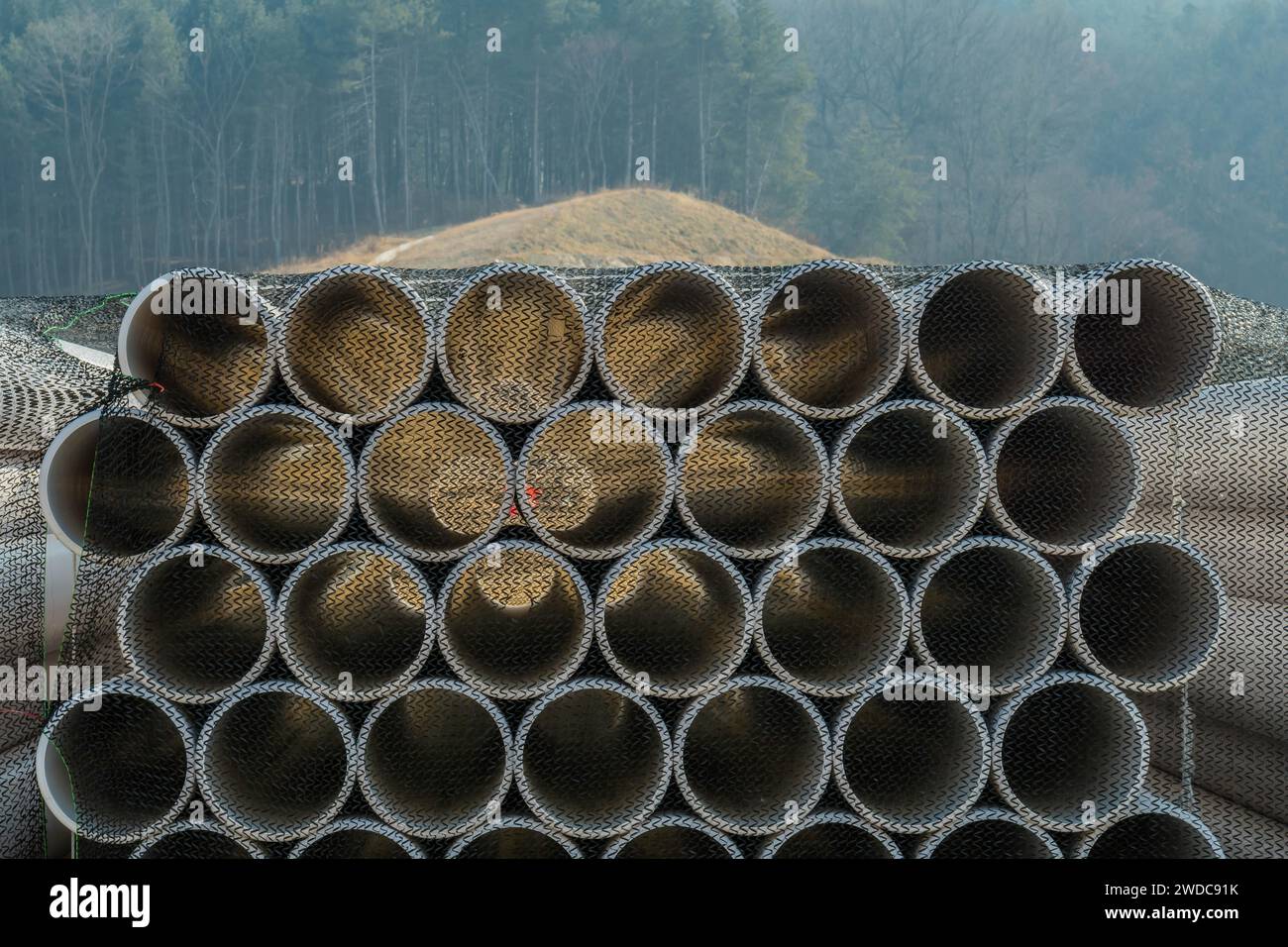 Stack of corrugated pipe covered with black mesh at construction site ...