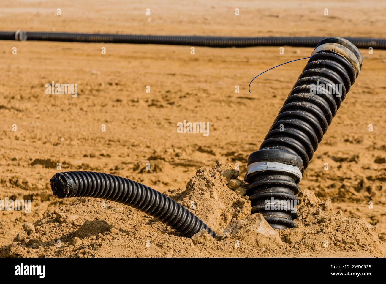 Closeup of corrugated pipe for plumping extruding from under ground at ...