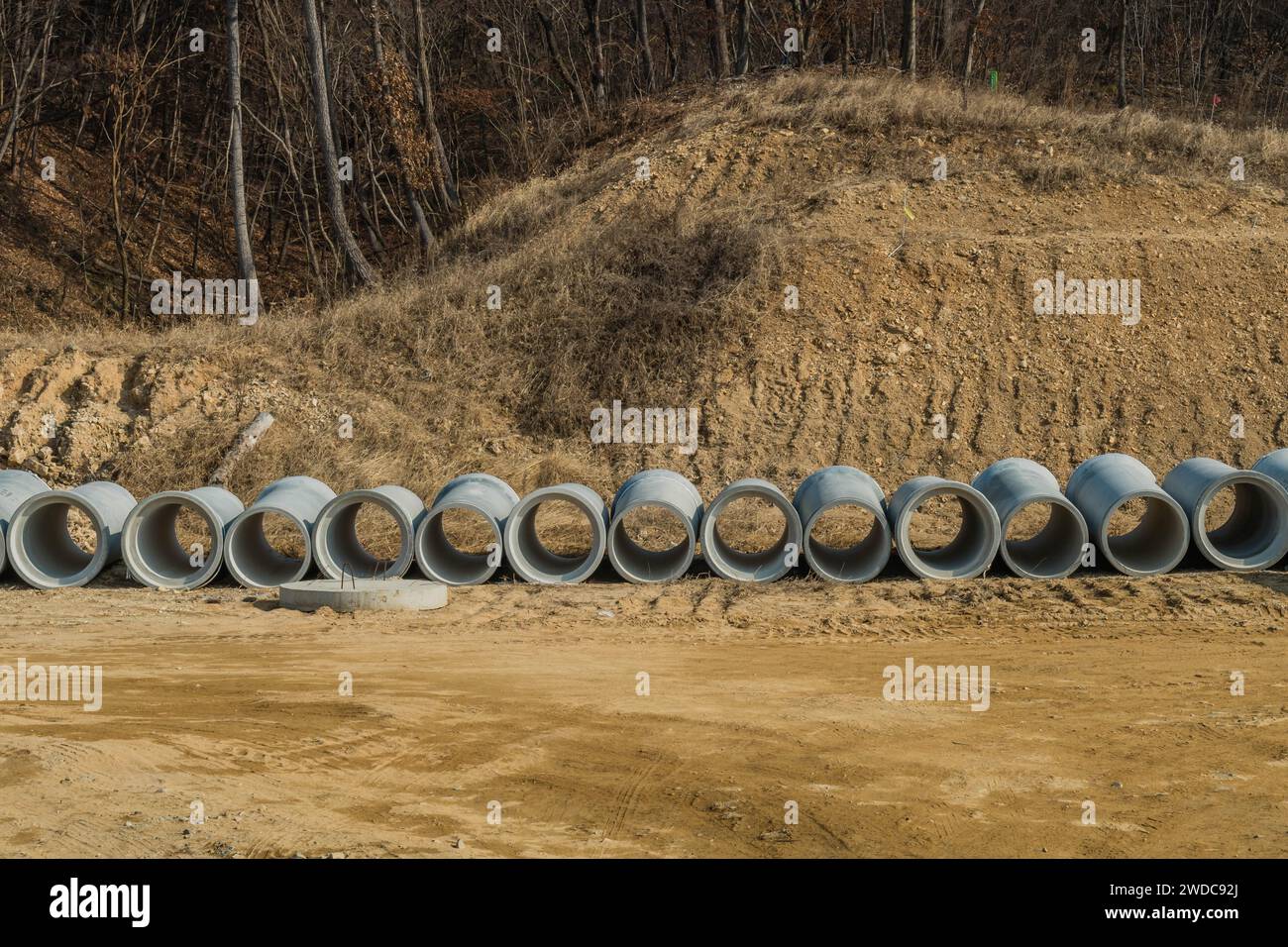 Large round concrete culverts at construction site with wooded area in ...