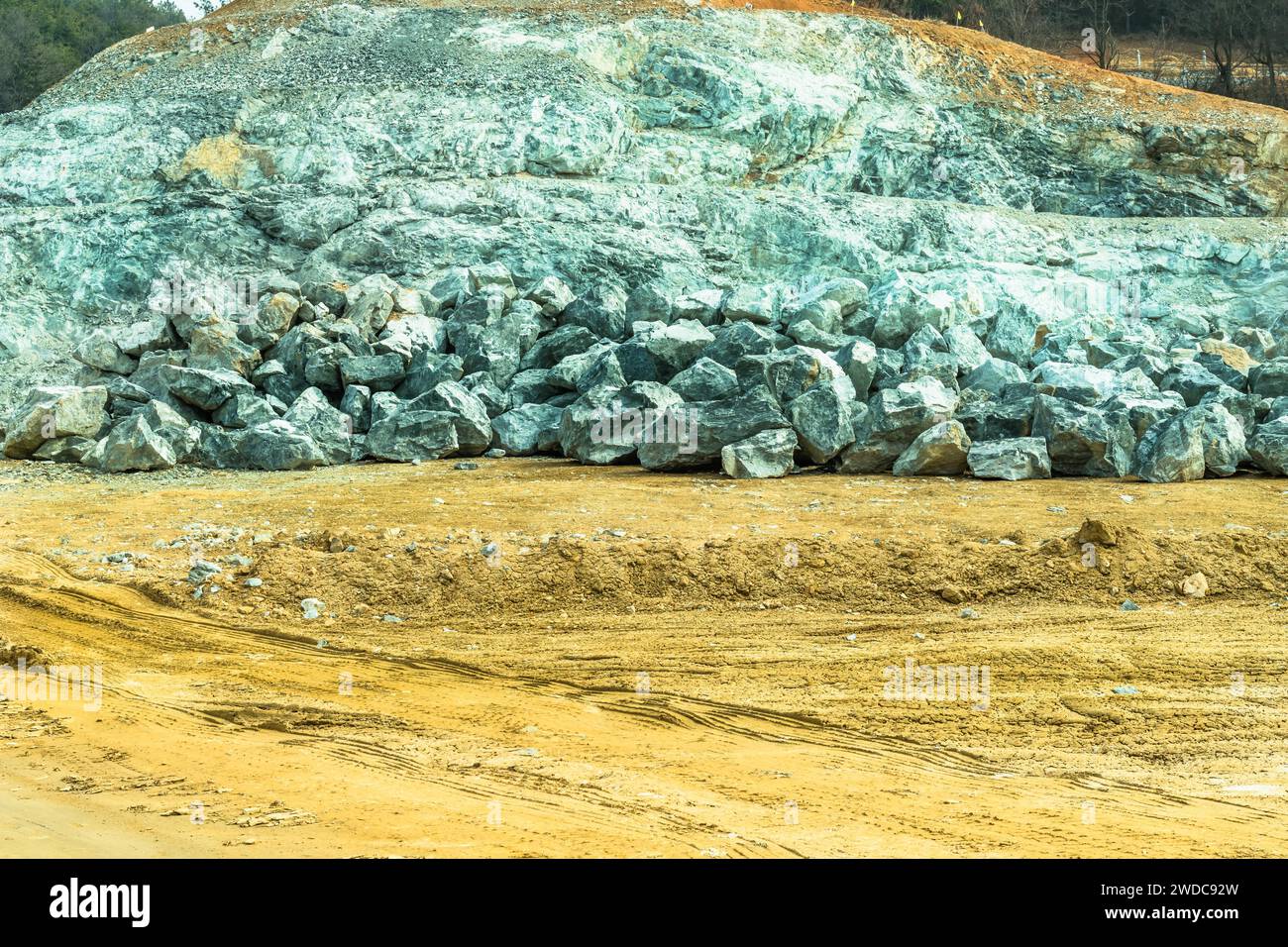 Pile of quarried boulders in front of granite wall at construction site ...