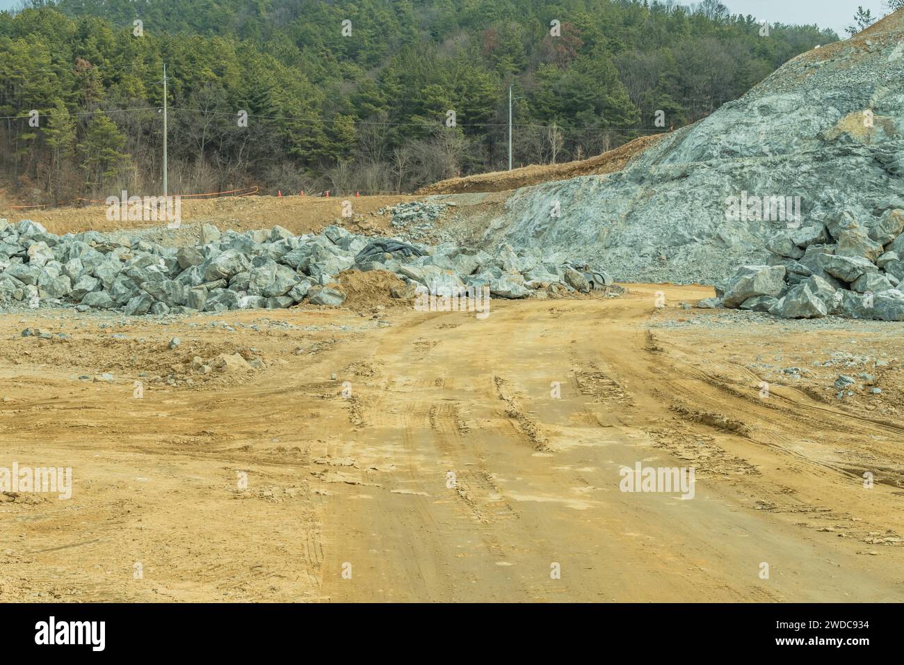 Pile of quarried boulders in front of granite wall at construction site ...