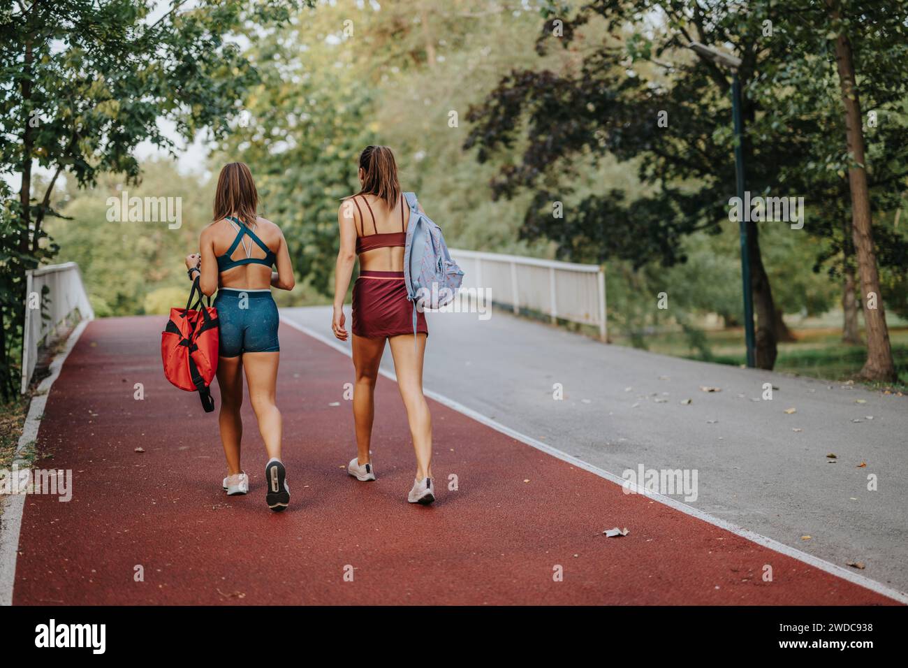 Gorgeous, fit girls walking through a green park after training. They ...