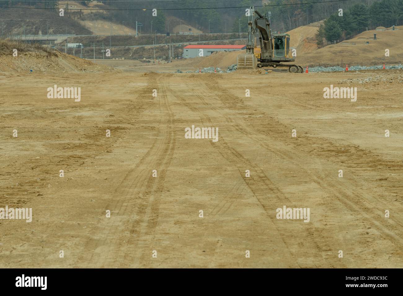 Tracks in dirt created by resting backhoe seen in distance at ...