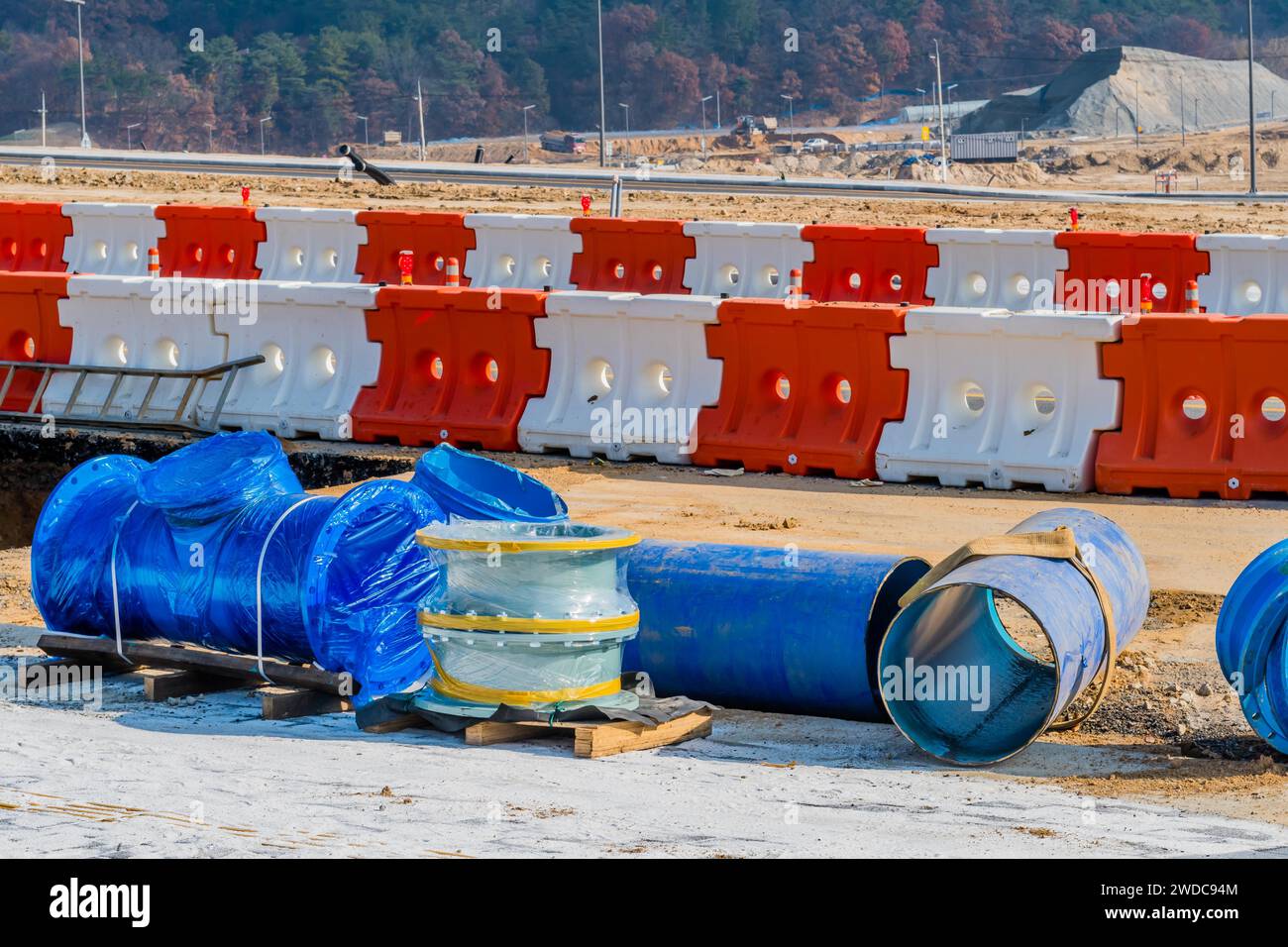 Metal industrial pipes laying on ground in front of orange and white ...