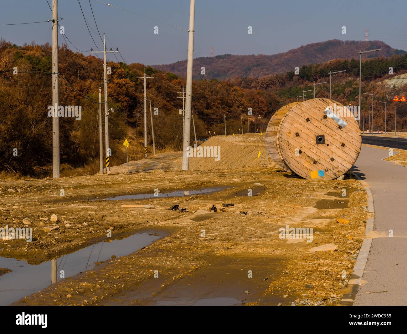 Large wooden industrial spools sitting on ground next to sidewalk of ...