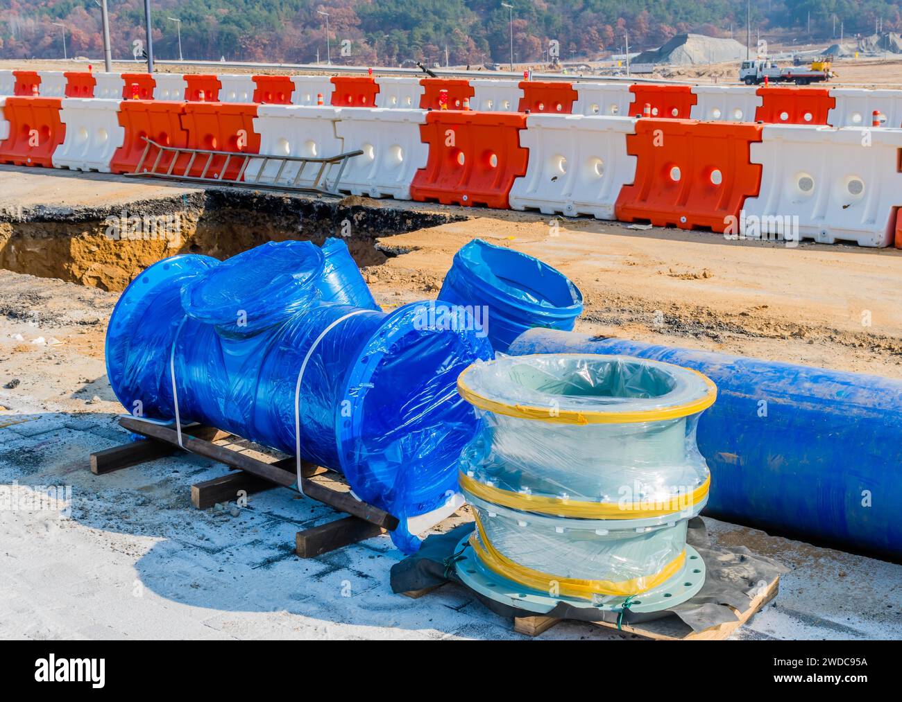 Metal industrial pipes laying on ground in front of orange and white ...