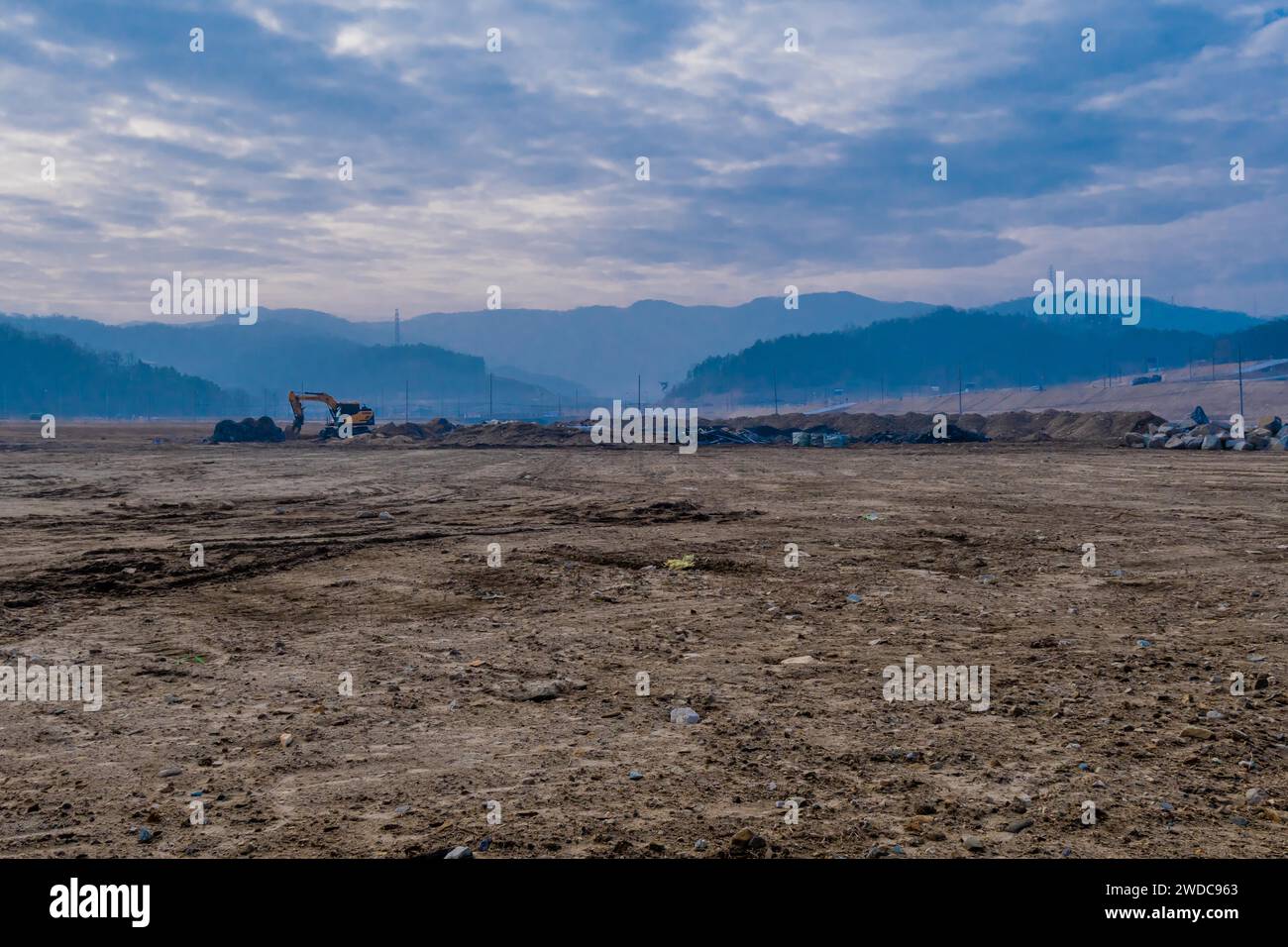 Landscape of new construction site with backhoe moving dirt in distance ...