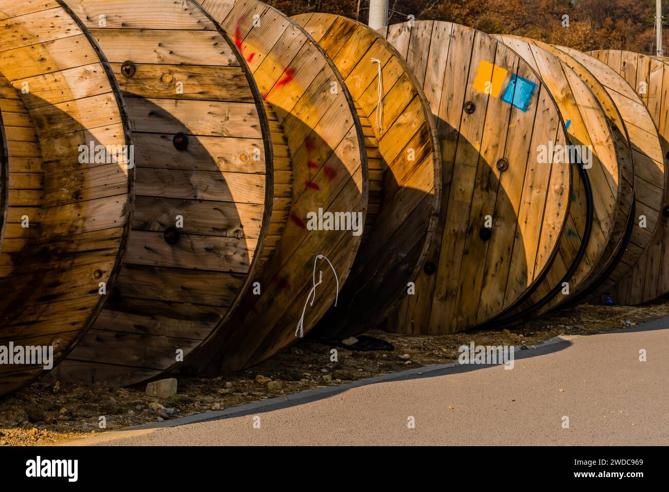 Large wooden industrial spools sitting on ground next to sidewalk of ...