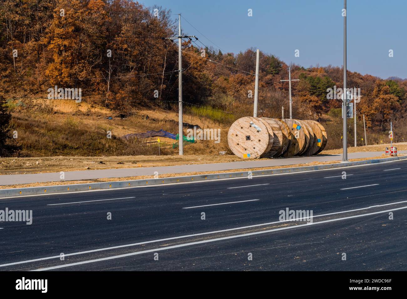 Large wooden industrial spools sitting on ground next to sidewalk of ...