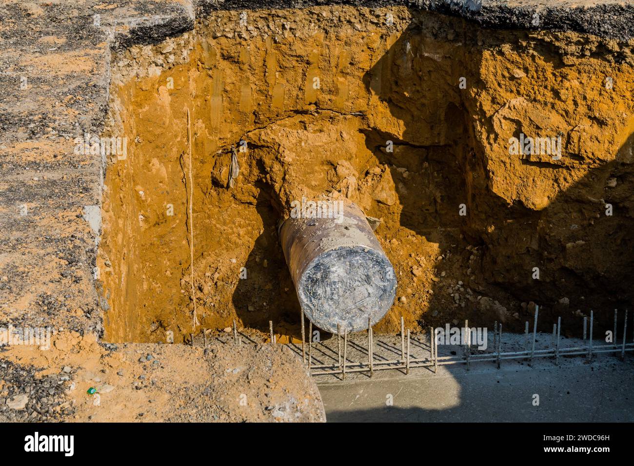 Large hole in paved road exposing water pipe covered with plastic ...