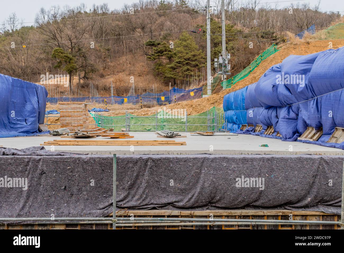 Unfinished concrete structure partially covered with blue tarp at new ...