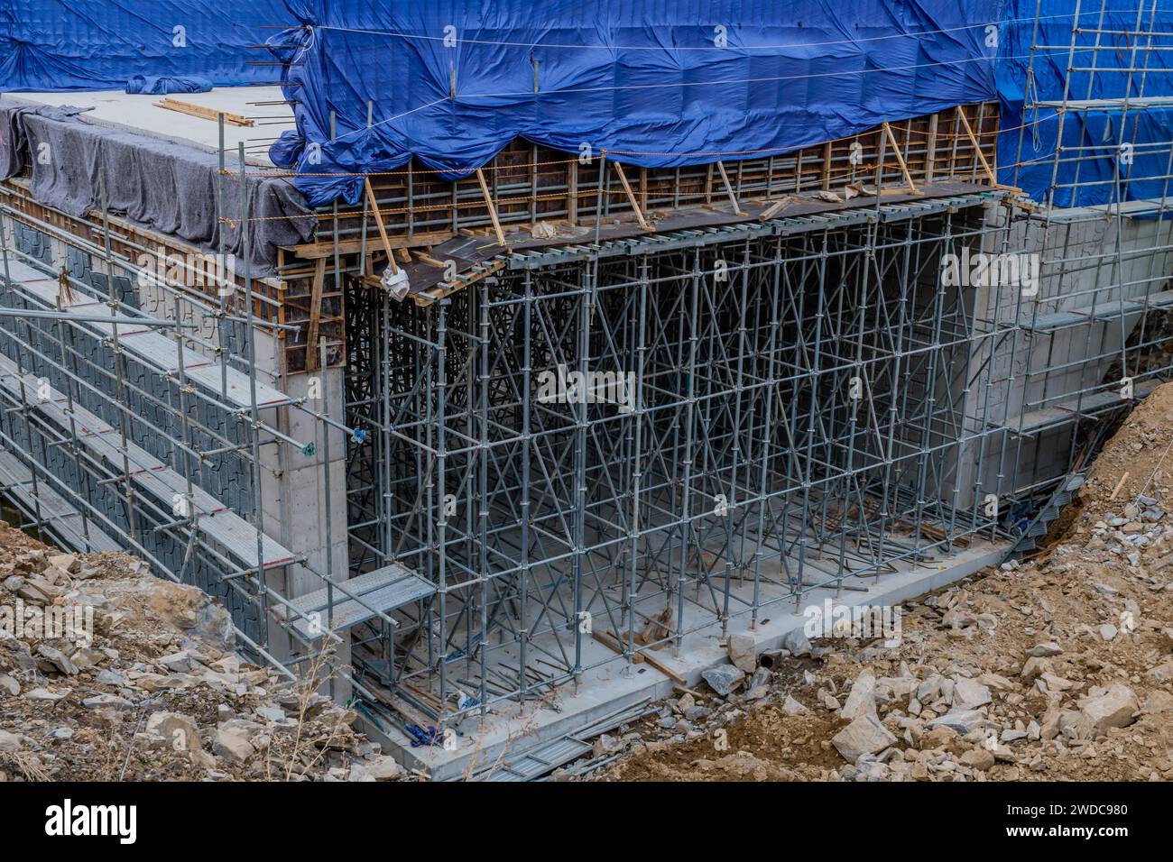 Unfinished concrete structure partially covered with blue tarp at new ...