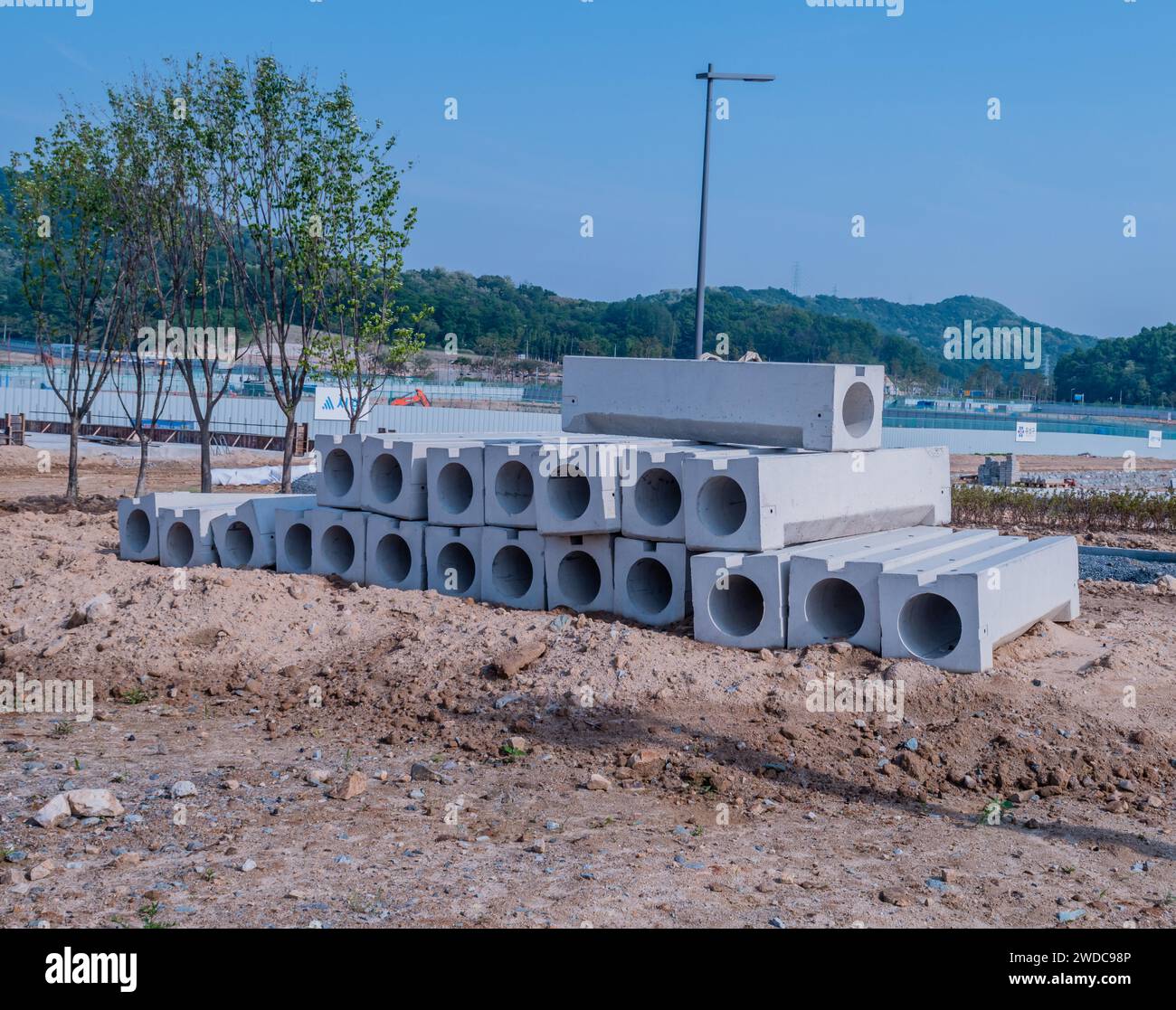 Square concrete columns stacked on ground at rural construction site ...
