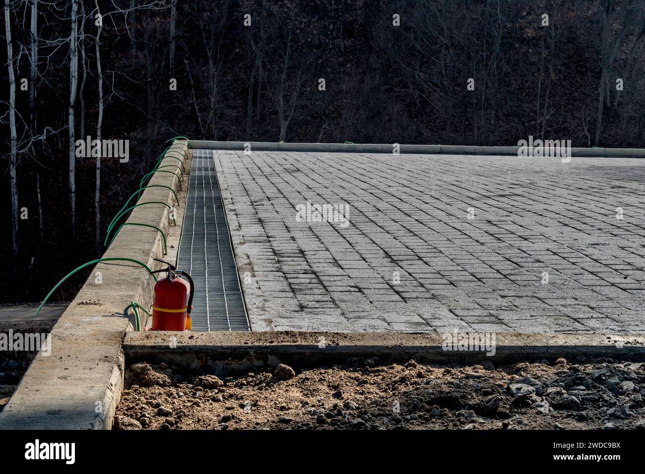 Small red hand held fire extinguisher outside at corner of concrete lot ...