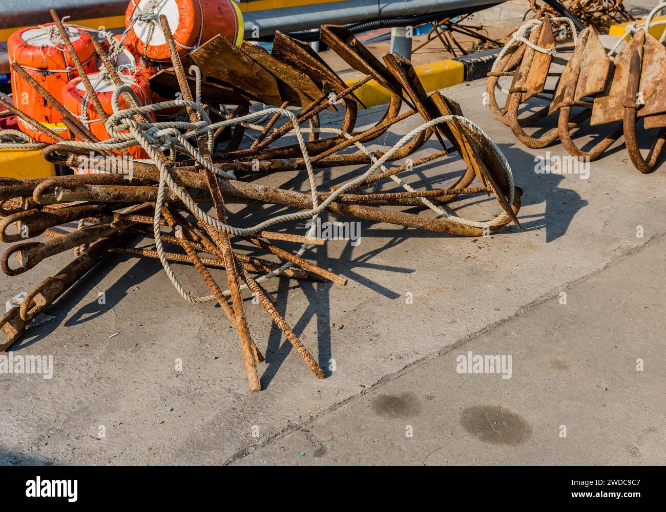 Collection of rusty anchors and styrofoam buoys beside guardrail in ...