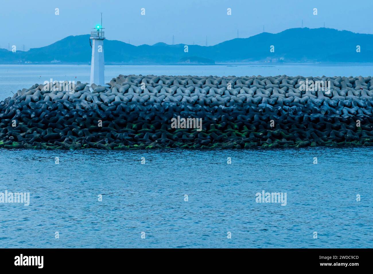 White lighthouse with green light on pier in seaport harbor, South ...