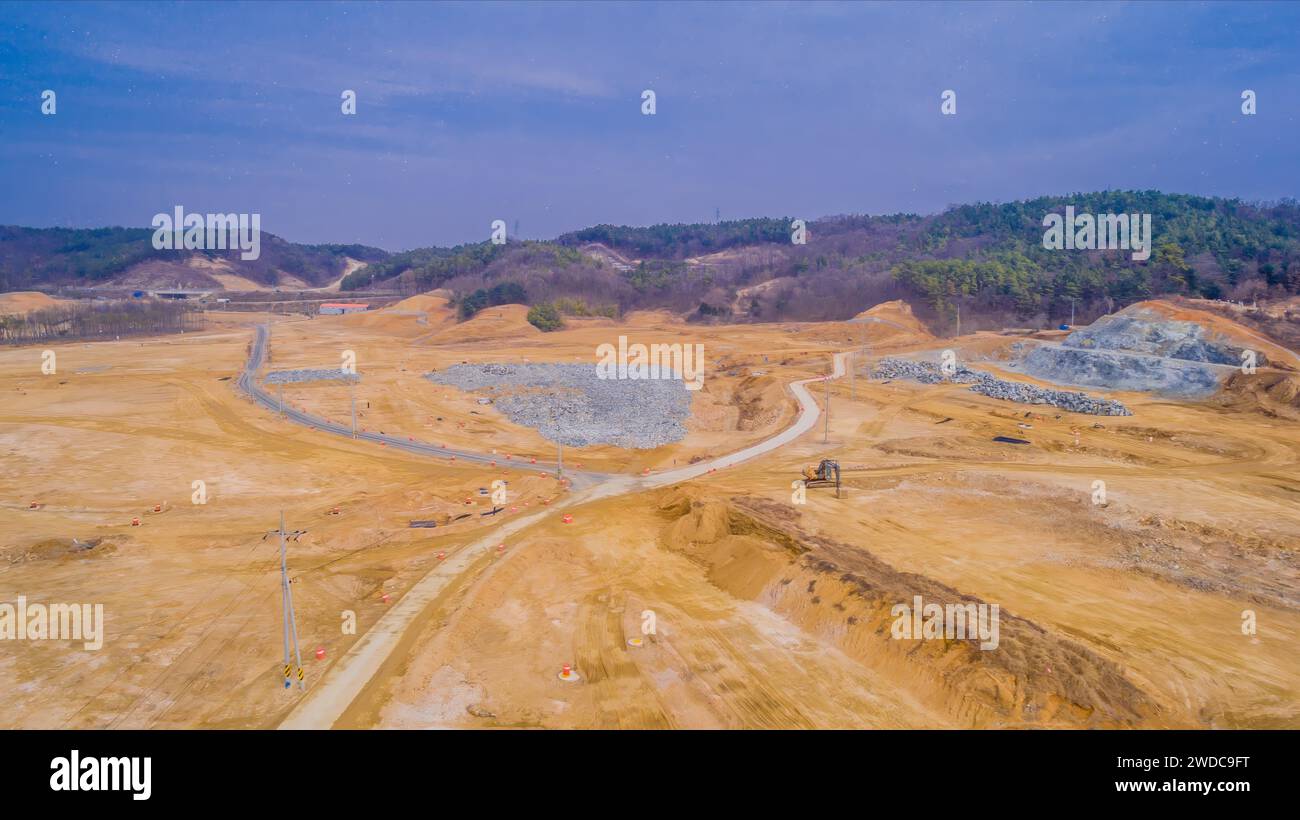 Aerial view of construction site with trees and rolling hills under ...