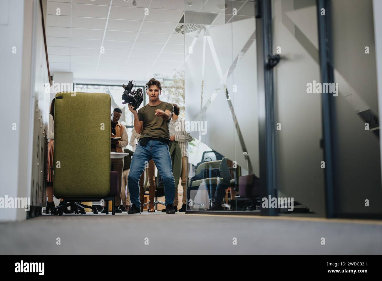 Positive, handsome cameraman dancing while taking a break from work ...