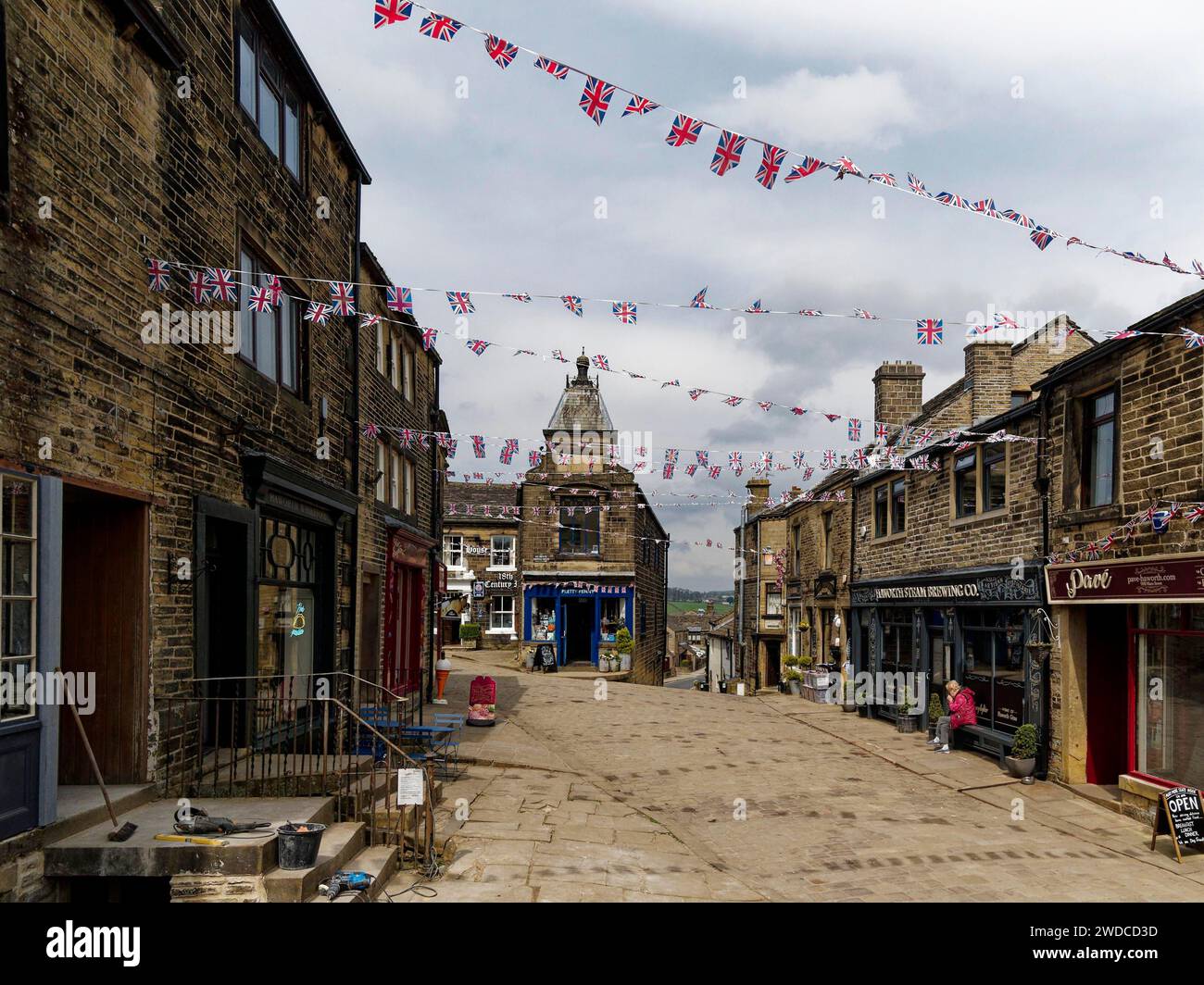 An old town street decorated with Union Jack flags on a cloudy day ...
