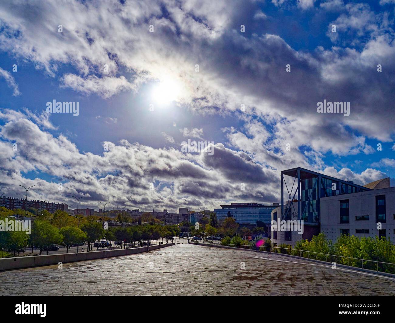 The sun shines through the clouds over an urban landscape with people ...