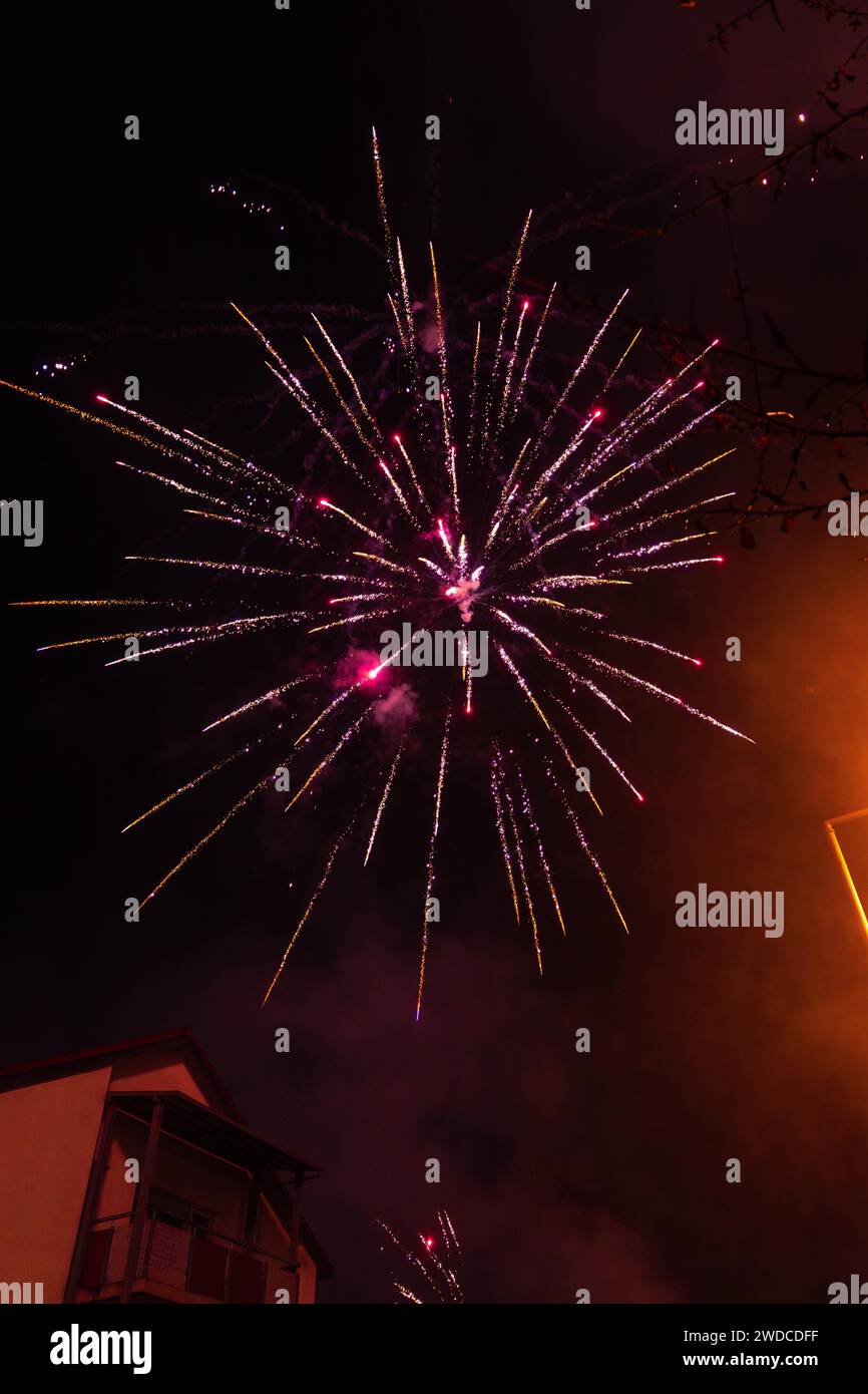 Sparkling fireworks light up the night sky above city buildings ...